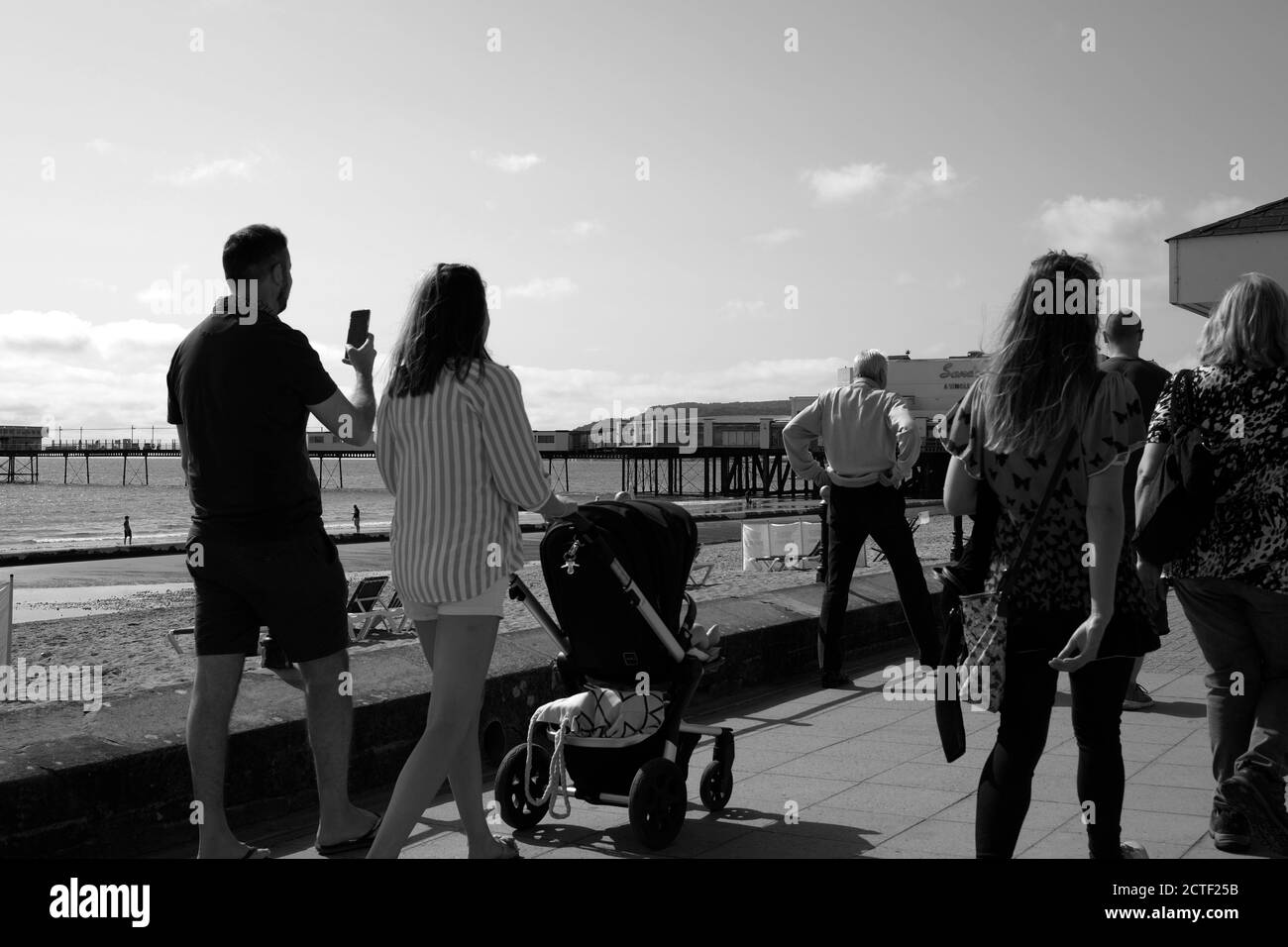 Sunday promenade along Sandown seafront several people woman pushing ...