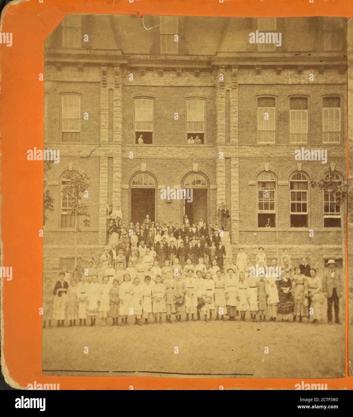 Boys and girls pose with adults on front steps of large brick ...