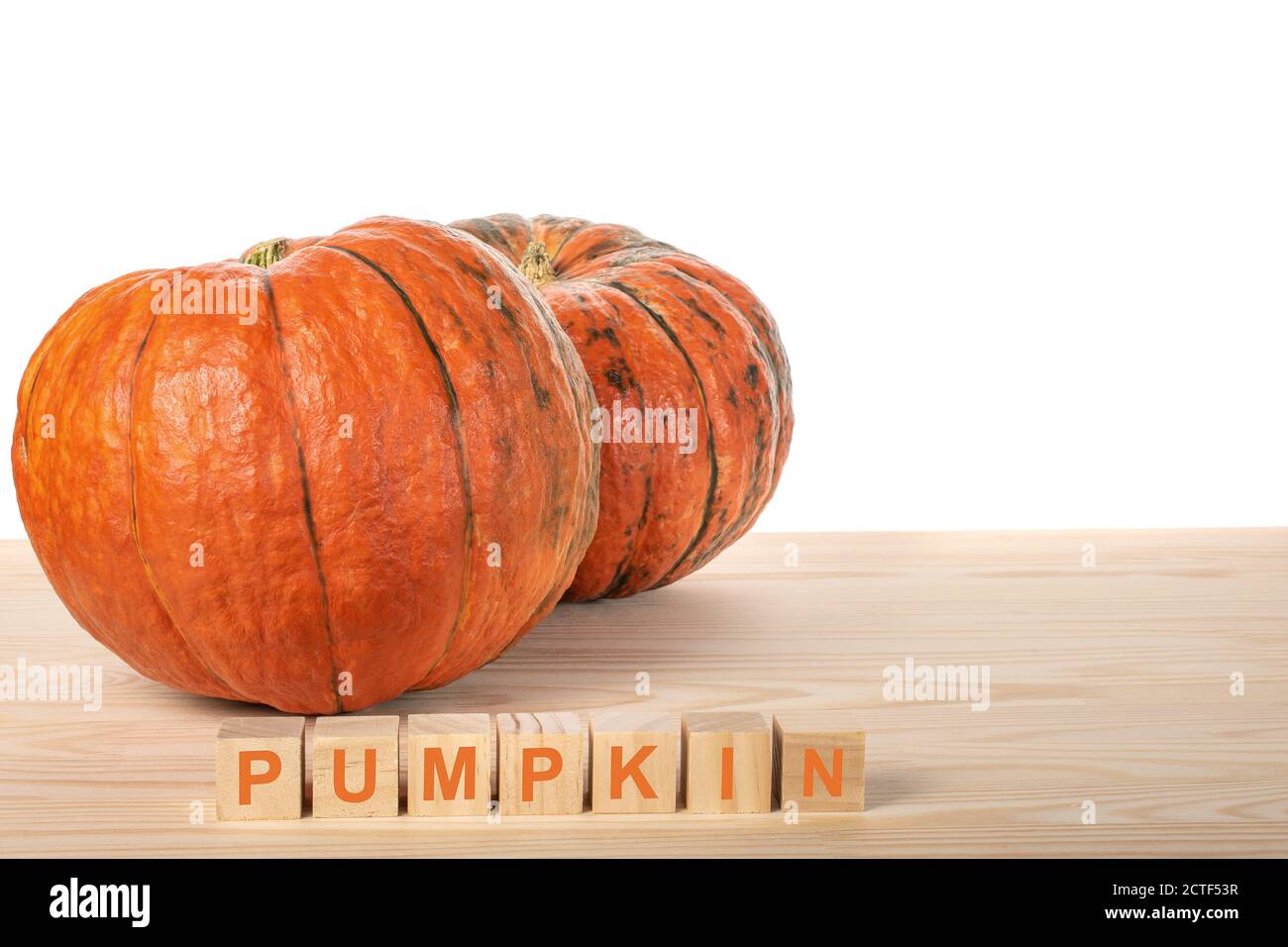 two pumpkins on a wooden table. the word PUMPKIN is laid out in wooden ...