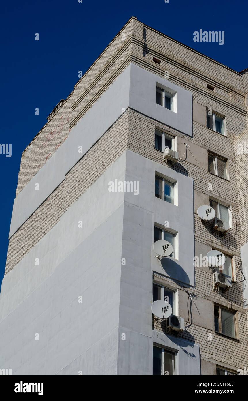 Facade of a multi-storey building with many satellite antennas. White ...