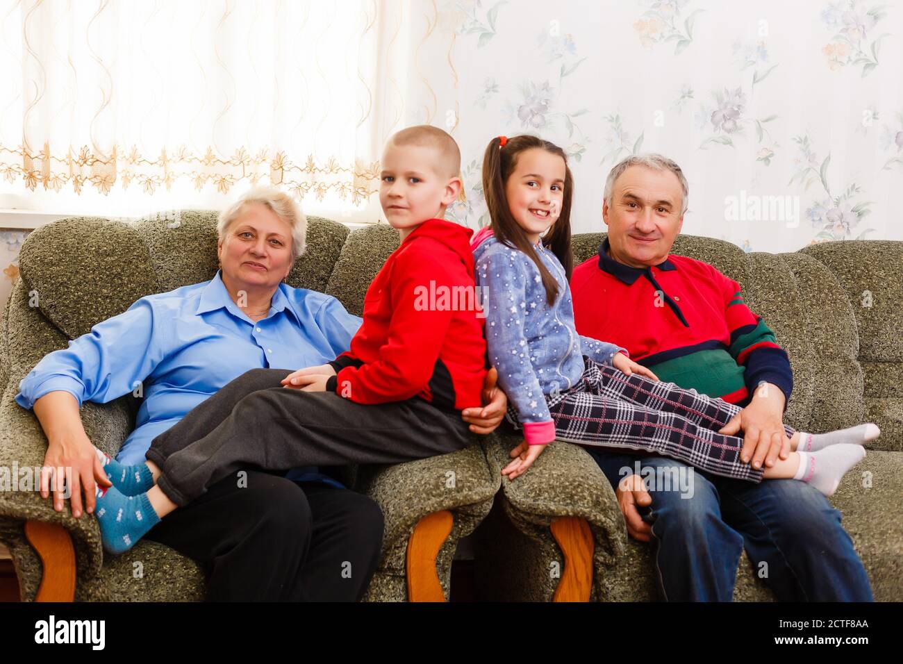 Grandparents and their young grandchildren relaxing at home Stock Photo ...
