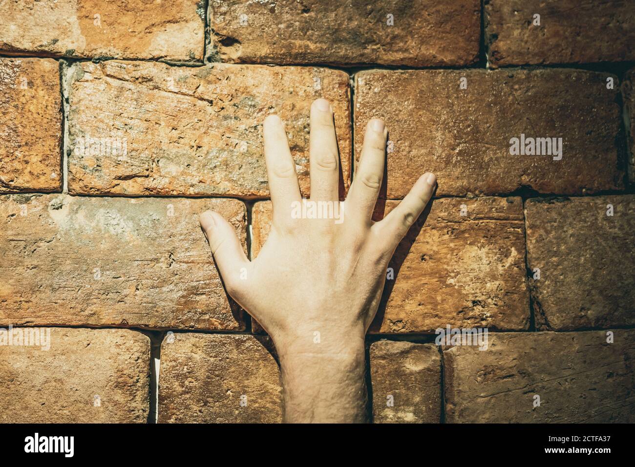 Close up view man hand wrist spread fingers on old vintage brown brick ...