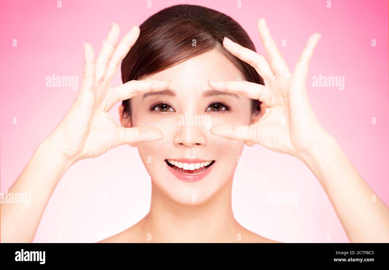 closeup young beauty and eye looking through fingers Stock Photo - Alamy