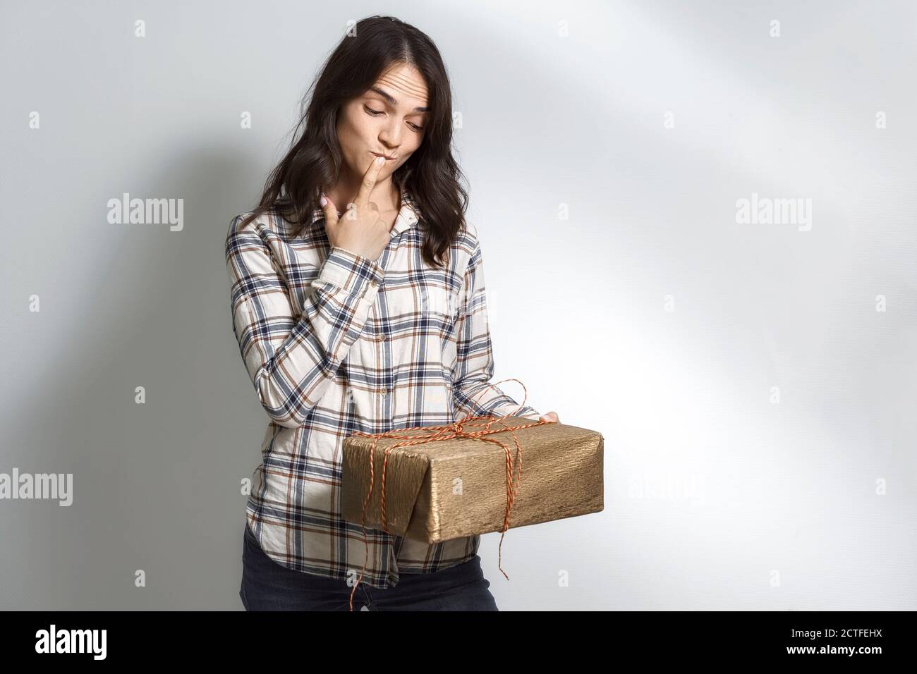 Beautiful woman with a gift box. the woman looks thoughtfully at the ...