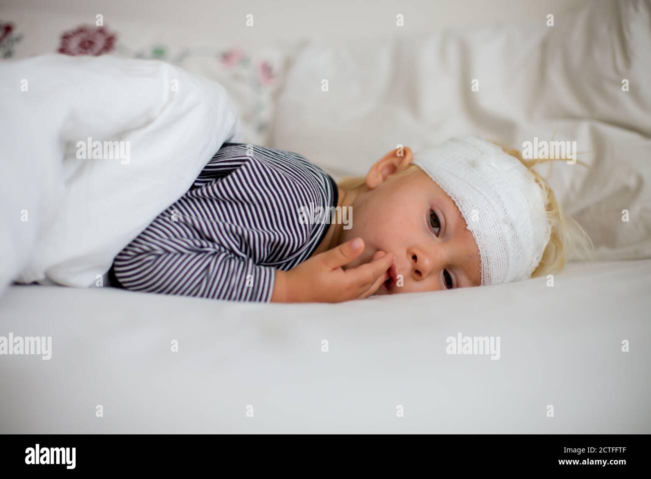 Little toddler boy with head injury, lying in bed, tired, sleeping ...