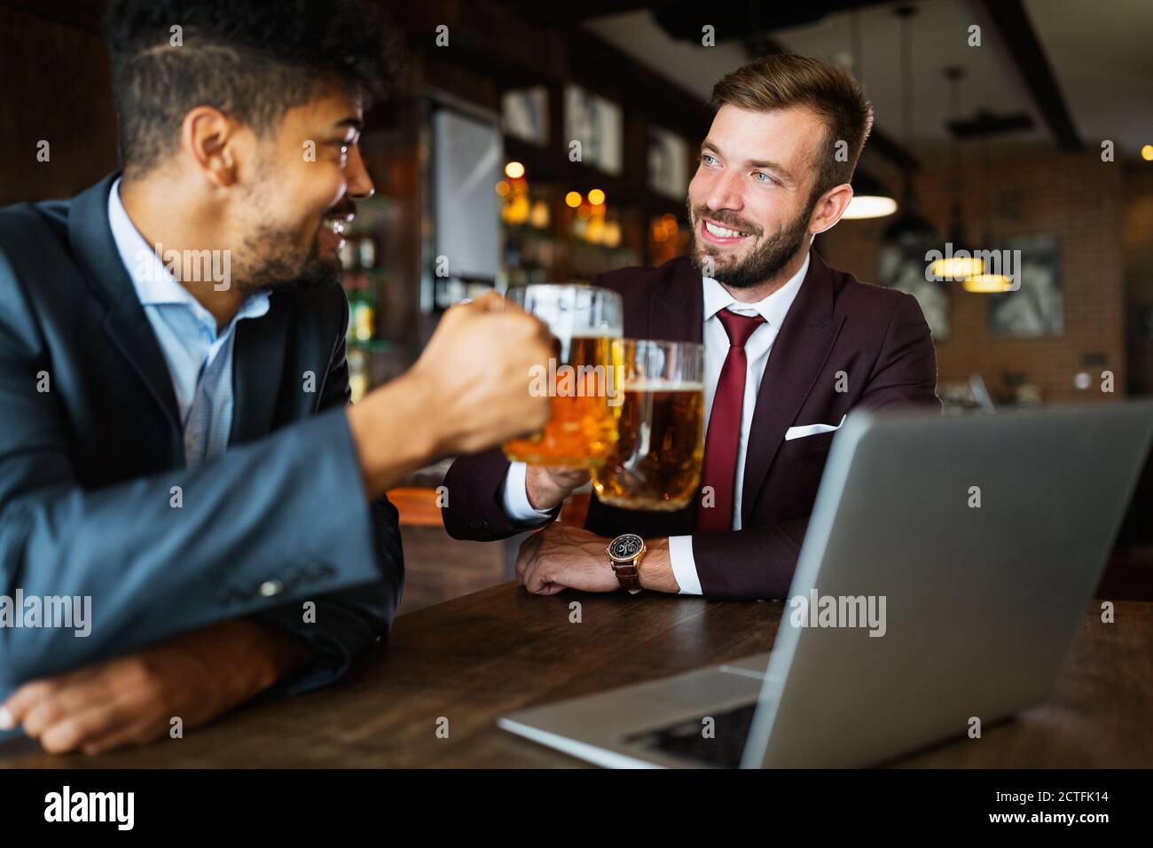 Having a pint with friend. Cheerful young men toasting with beer while ...