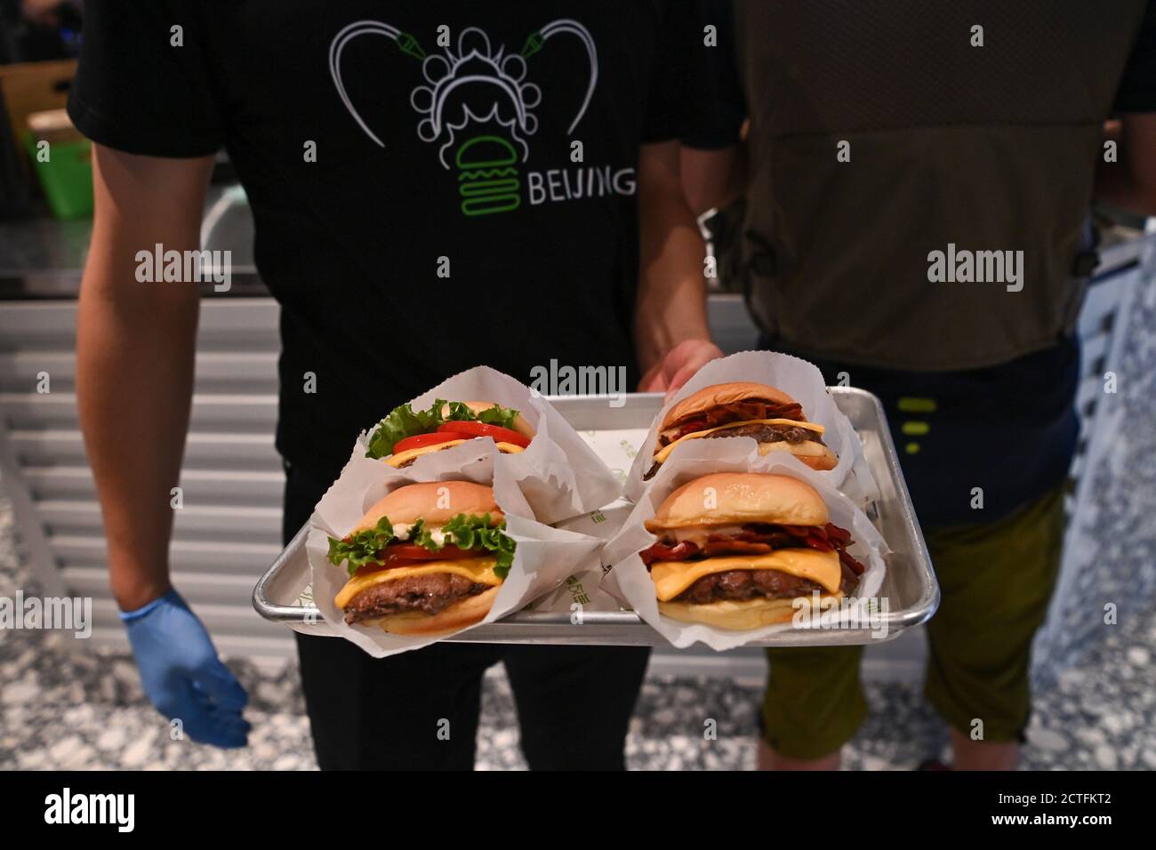 A staff shows the burgers made at the Shake Shack store at Sanlitun in ...