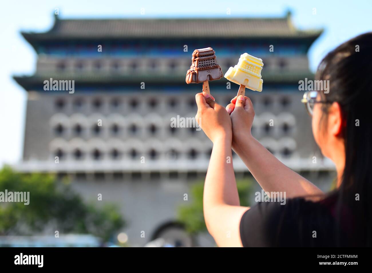 A person shows the ice-cream against the Zhengyang Gate on Qianmen ...