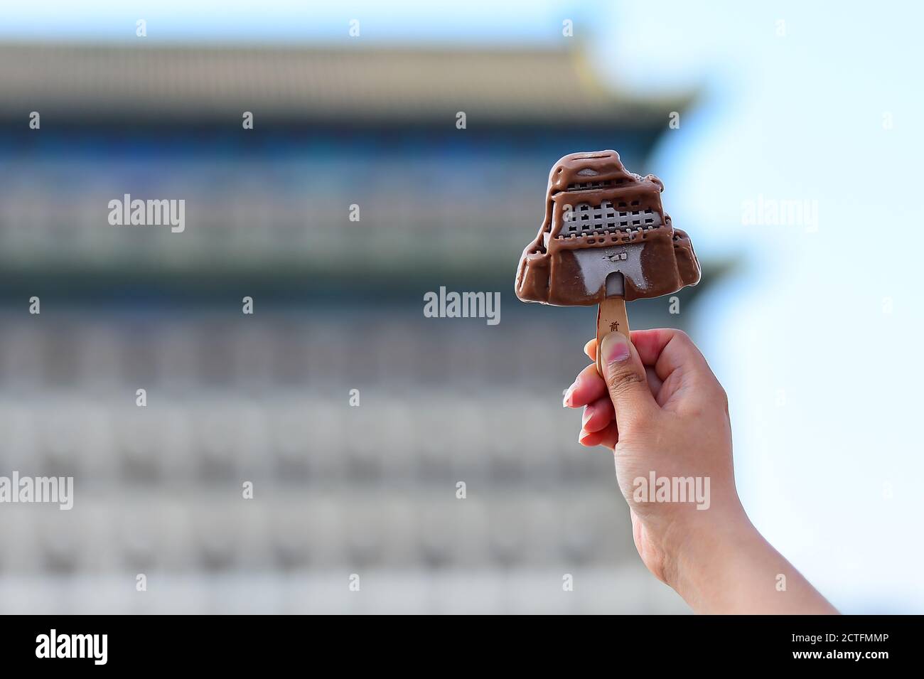 A person shows the ice-cream against the Zhengyang Gate on Qianmen ...