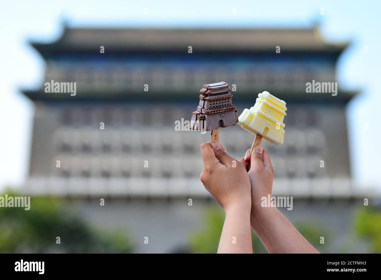 A person shows the ice-cream against the Zhengyang Gate on Qianmen ...