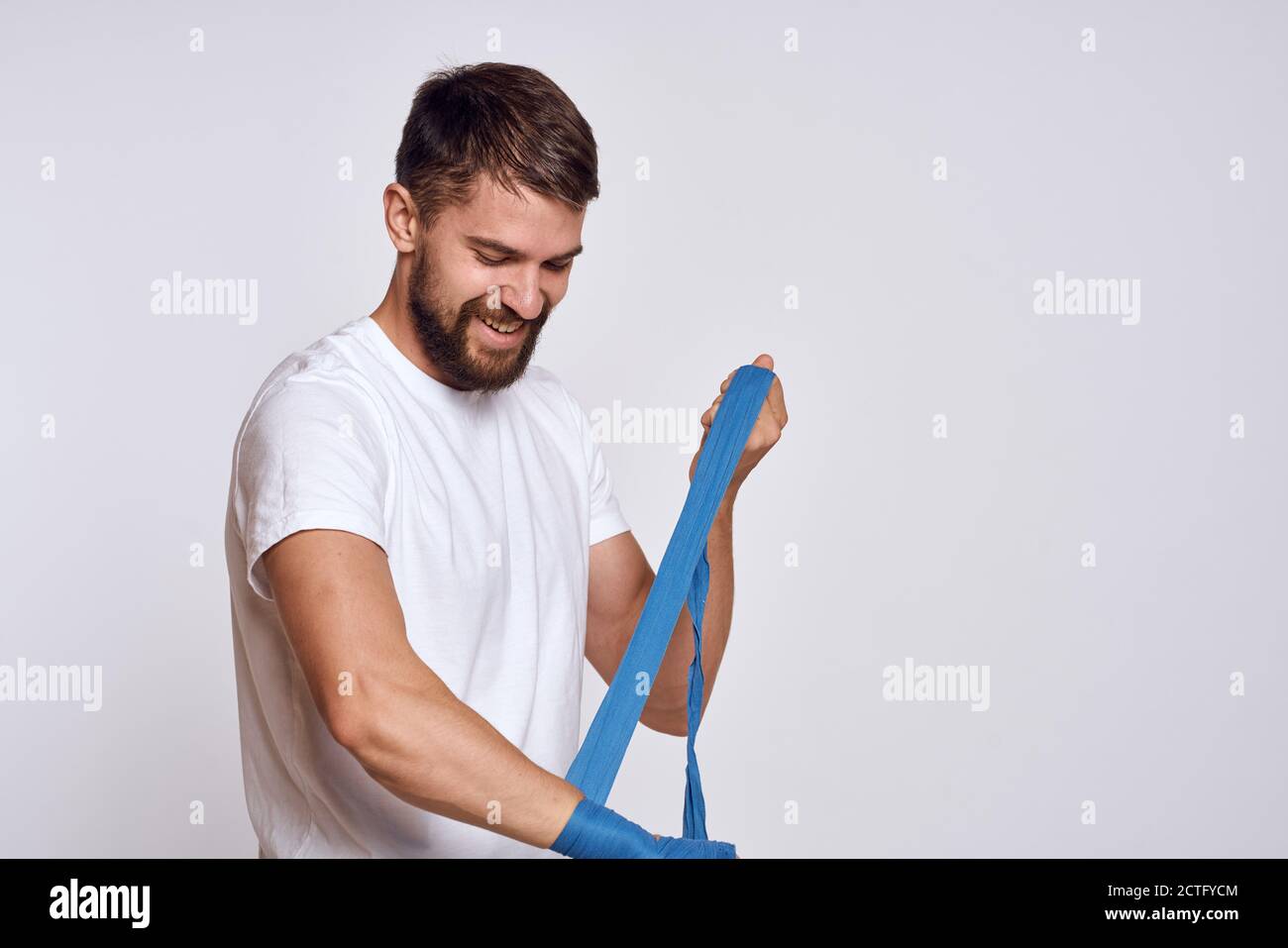 A sportive man in a white T-shirt boxing bandages on his hands ...