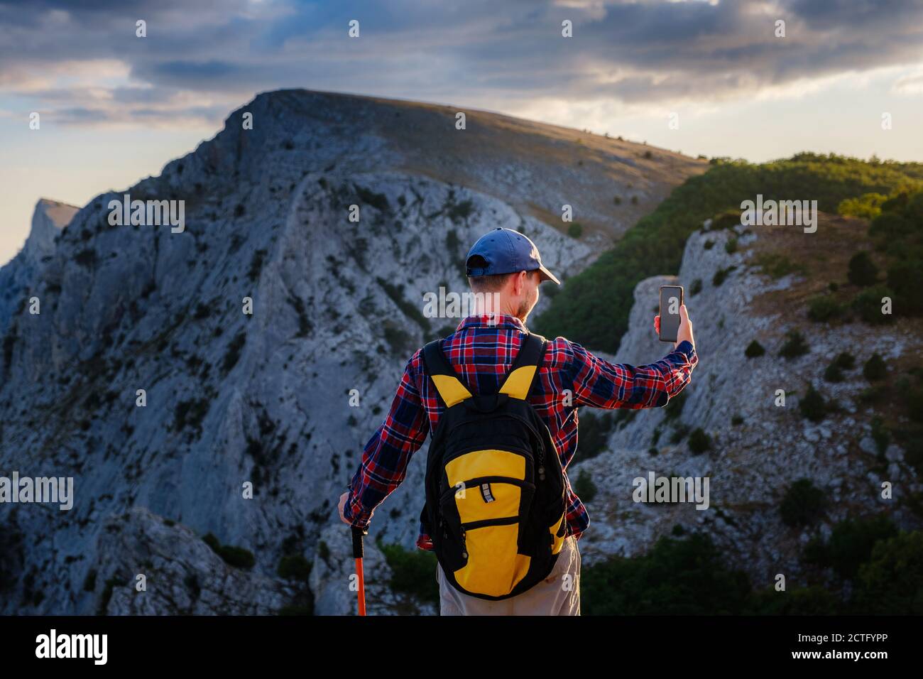 Strong man hiker taking photo with smart phone at mountain peak ...