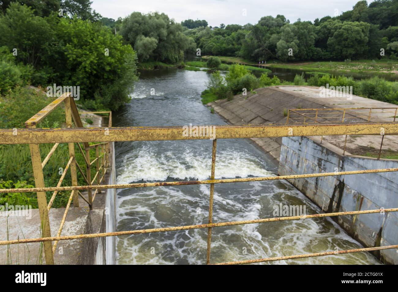 Midsummer. A metal fence at the discharge of water from a reservoir on ...