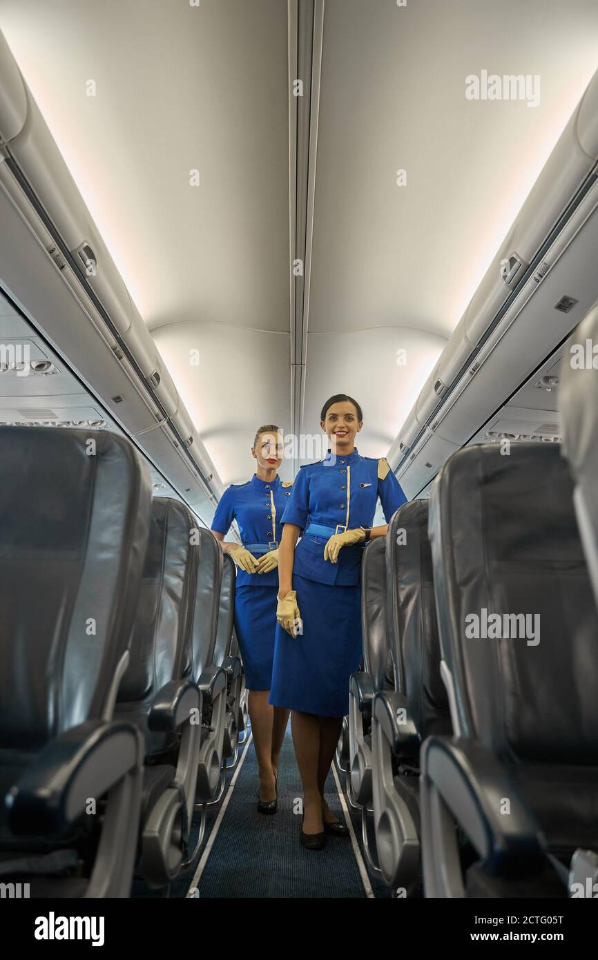 Two beautiful flight attendants standing between the seat rows Stock ...