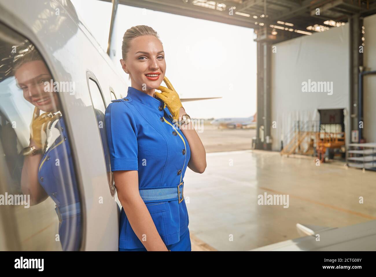 Beautiful stewardess posing near the modern aircraft Stock Photo - Alamy