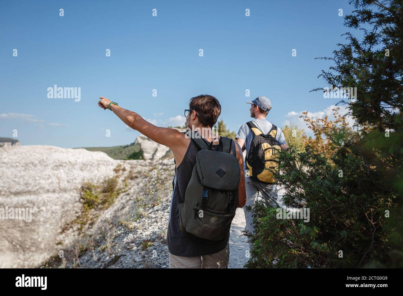 Two Hikers with Backpacks and other climbing Gear staying on top of ...