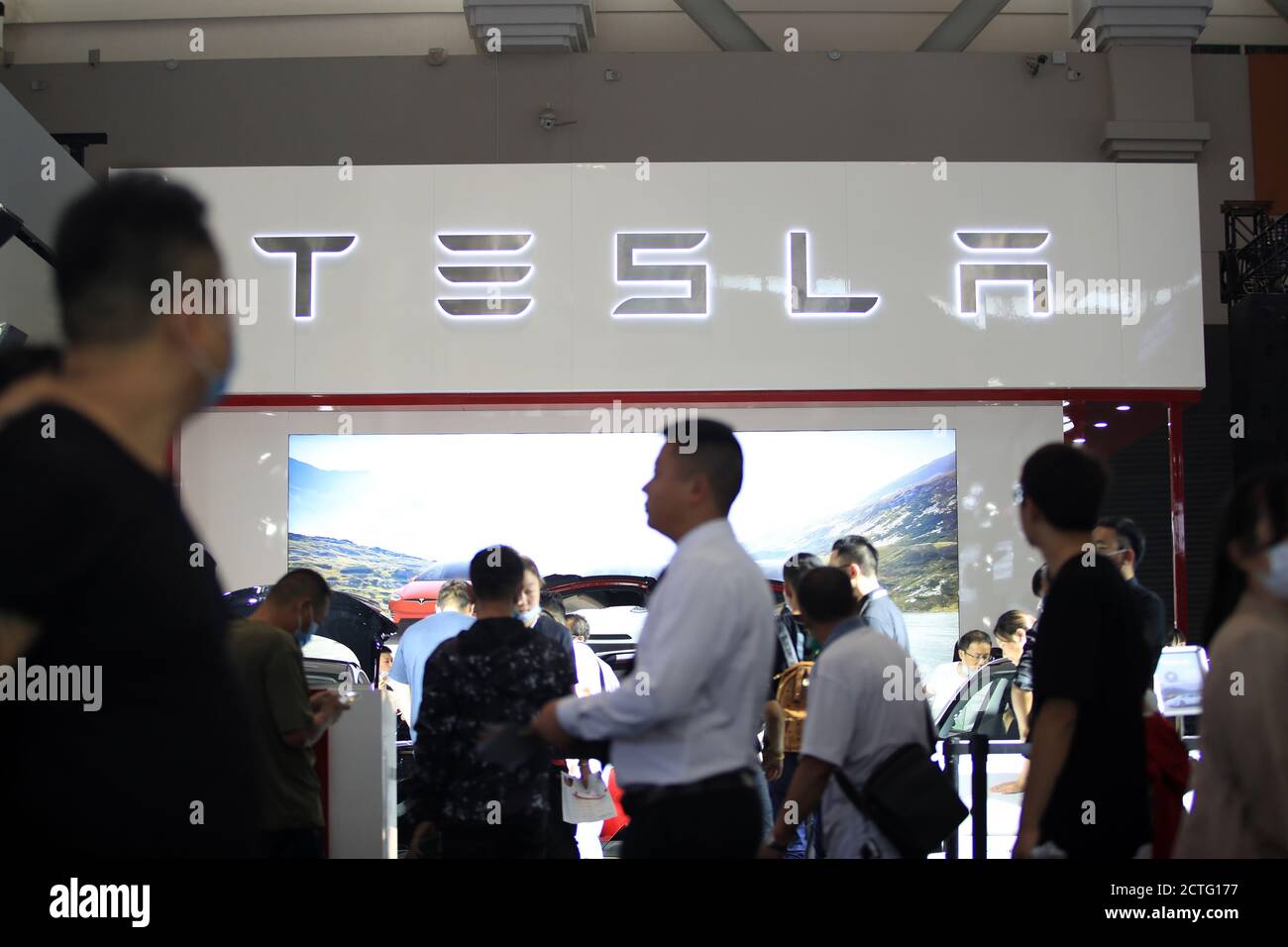 Visitors flock to the booth of Tesla, an American electric vehicle and ...