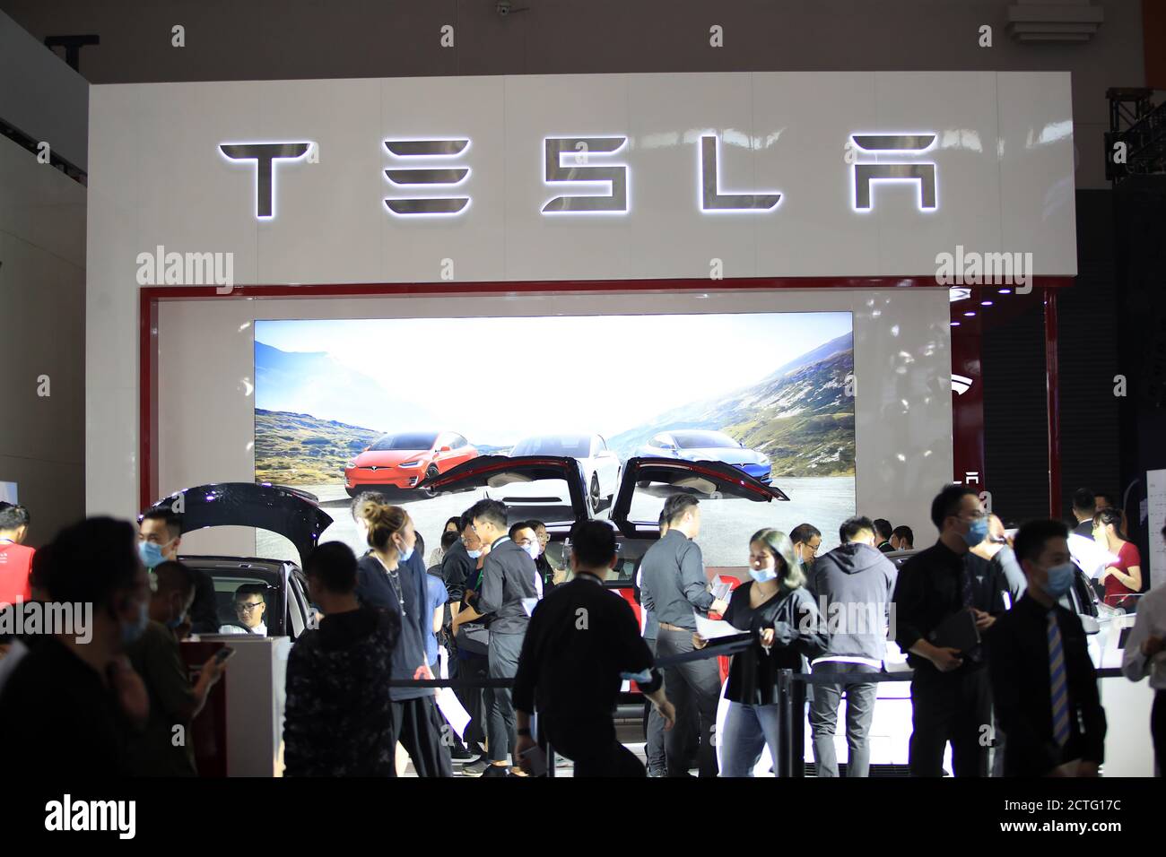 Visitors flock to the booth of Tesla, an American electric vehicle and ...