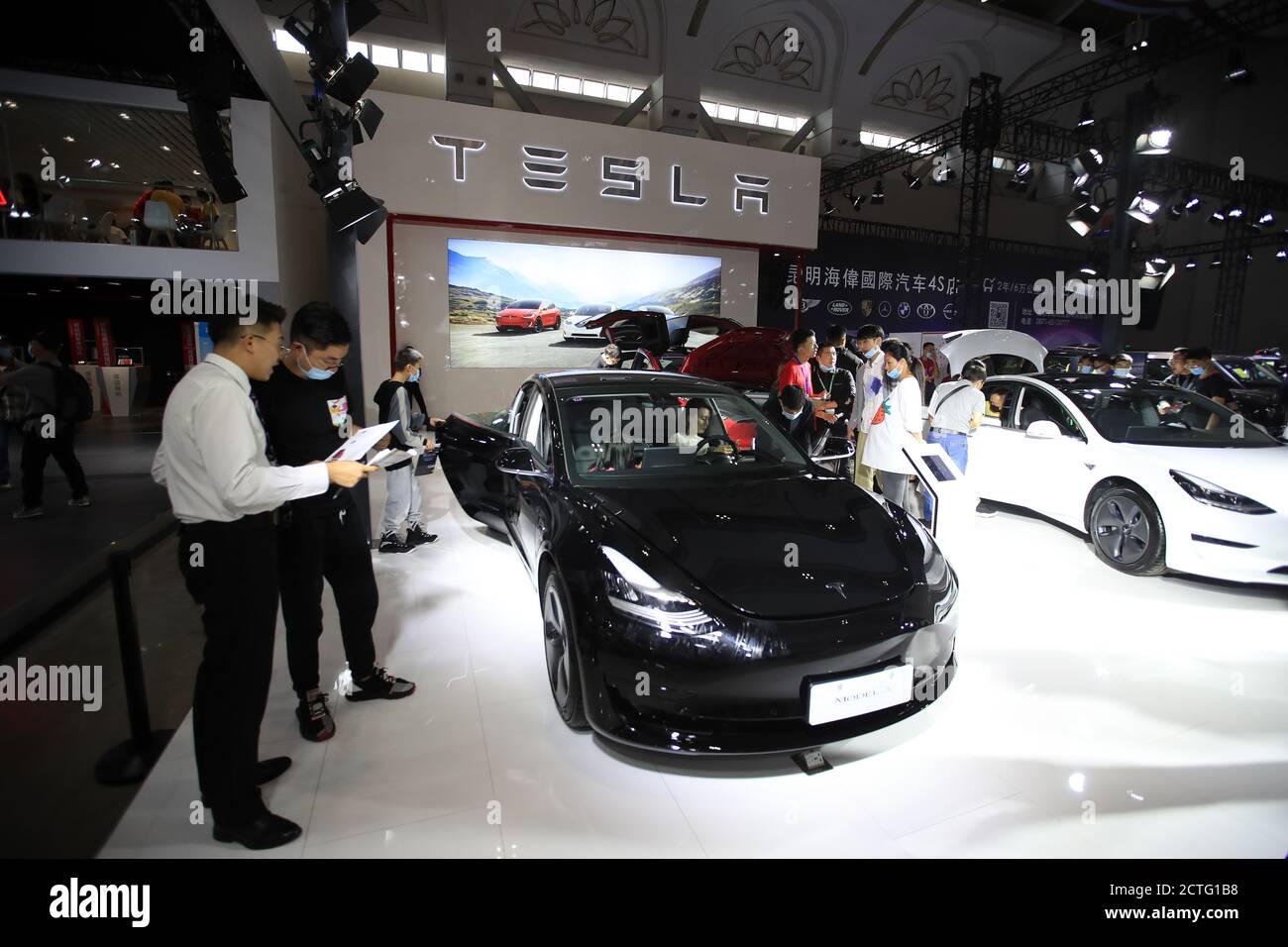 Visitors flock to the booth of Tesla, an American electric vehicle and ...