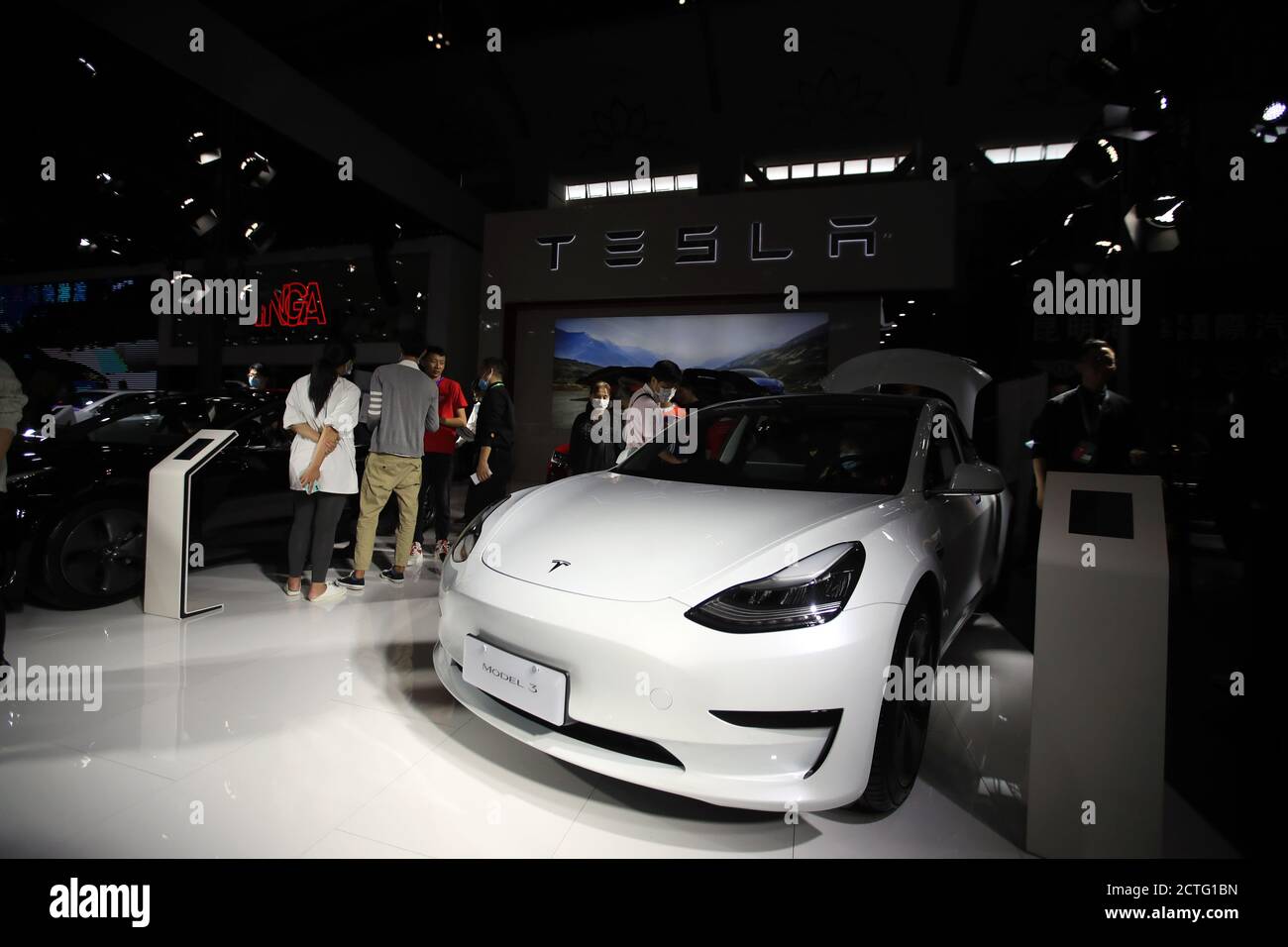 Visitors flock to the booth of Tesla, an American electric vehicle and ...