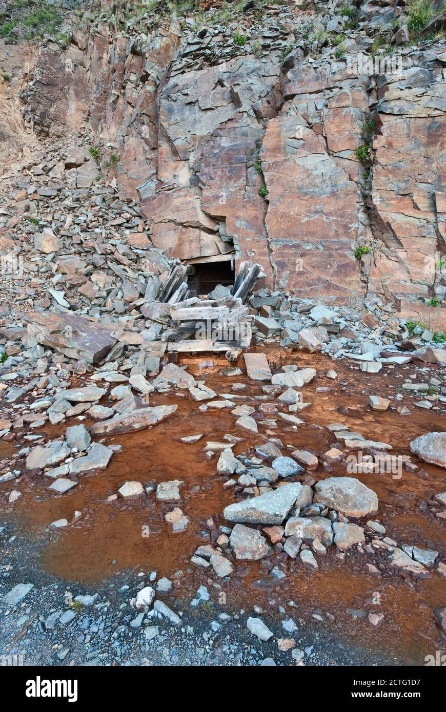 Adit entrance to underground gold mine, rust colored water coming out ...