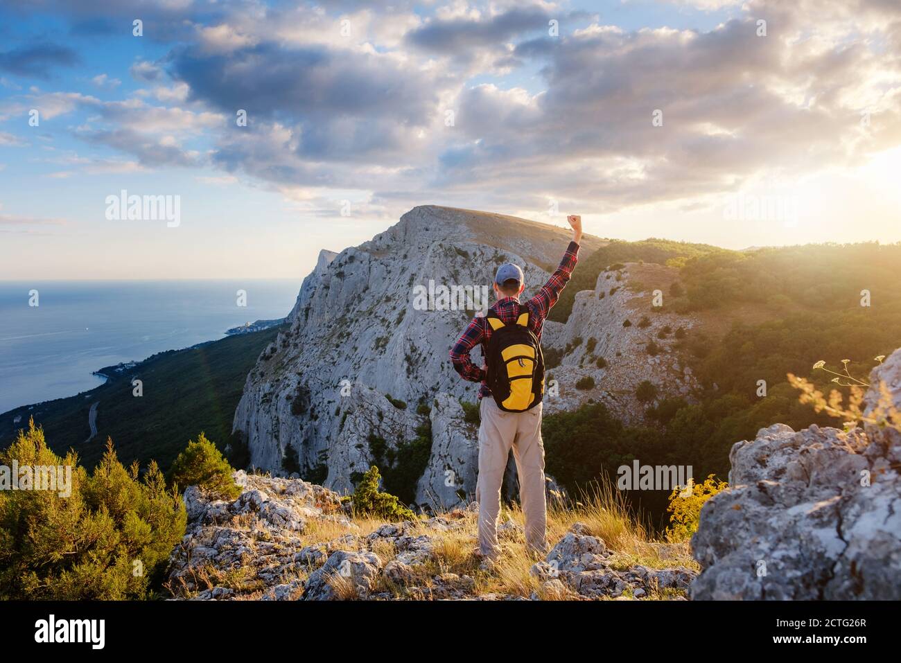Adventurous man is on top of the mountain and with raised hands and ...