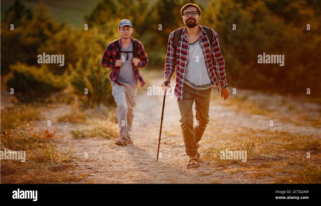 two men hikers enjoy a walk in nature, sunset time in summer. enjoying ...