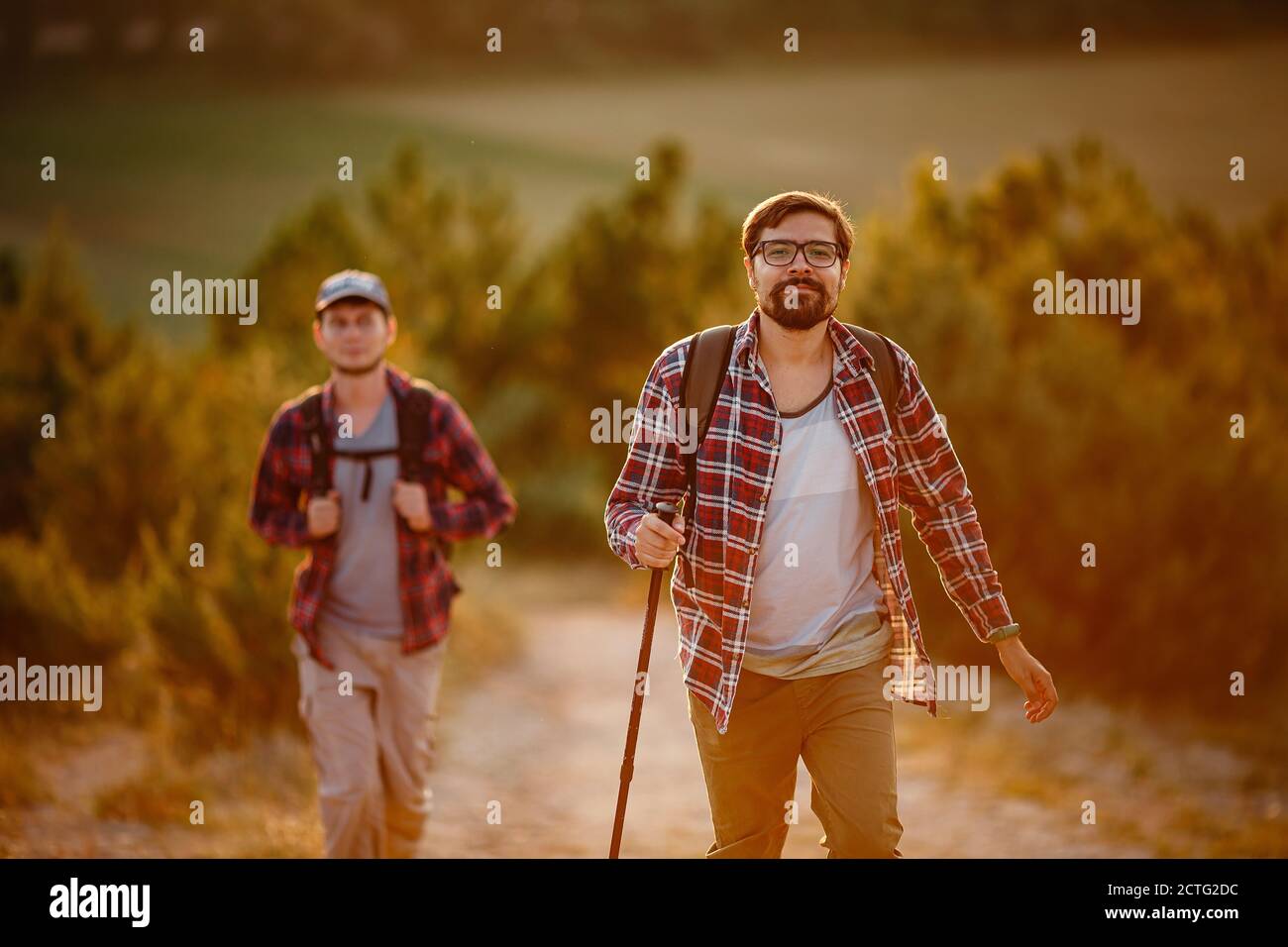 two men hikers enjoy a walk in nature, sunset time in summer. enjoying ...