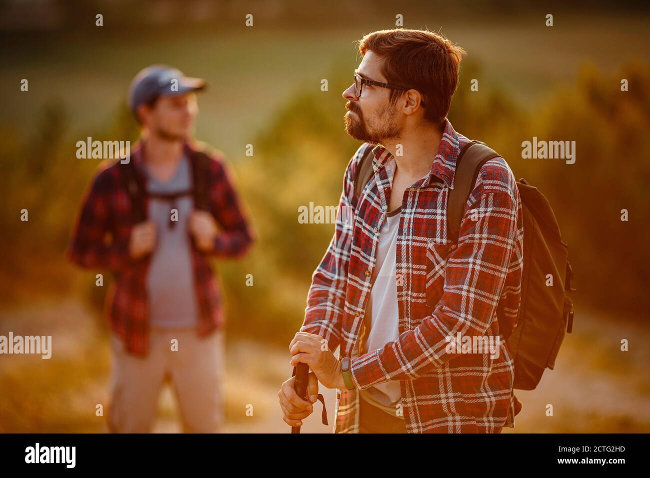 two men hikers enjoy a walk in nature, sunset time in summer. enjoying ...