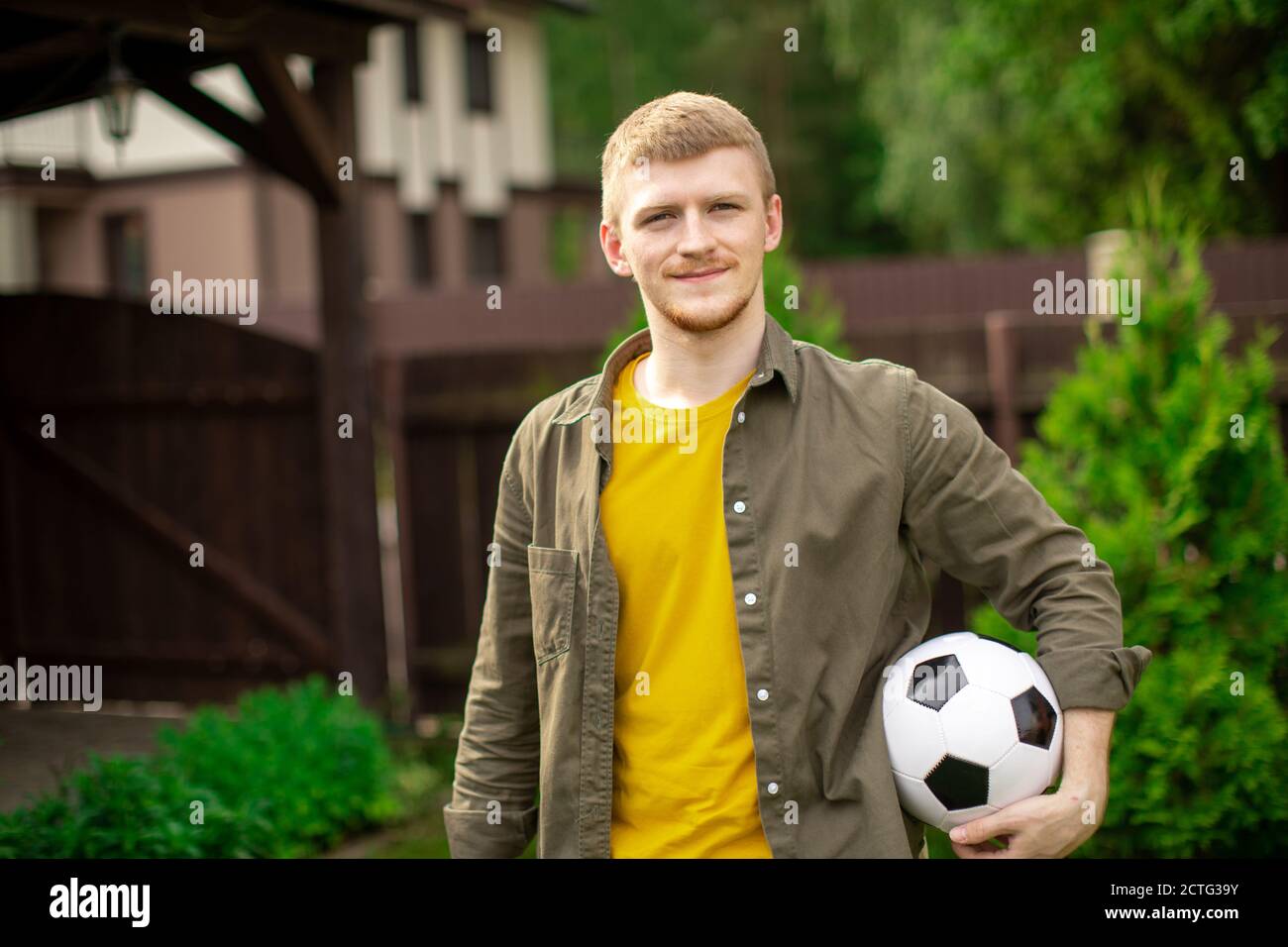 Happy male football fan with soccer ball looks at camera with smile ...