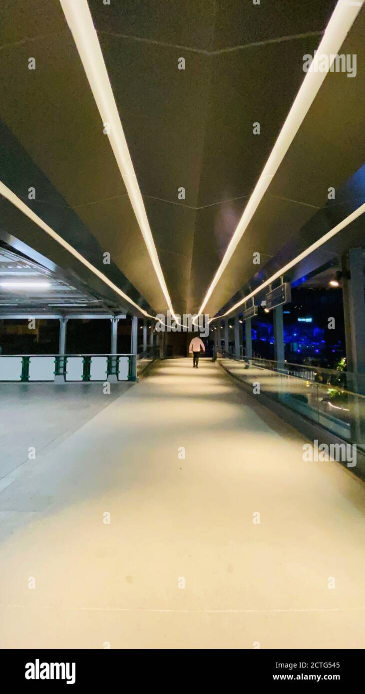 Walkway night lone man walks away strip lights over head Stock Photo ...