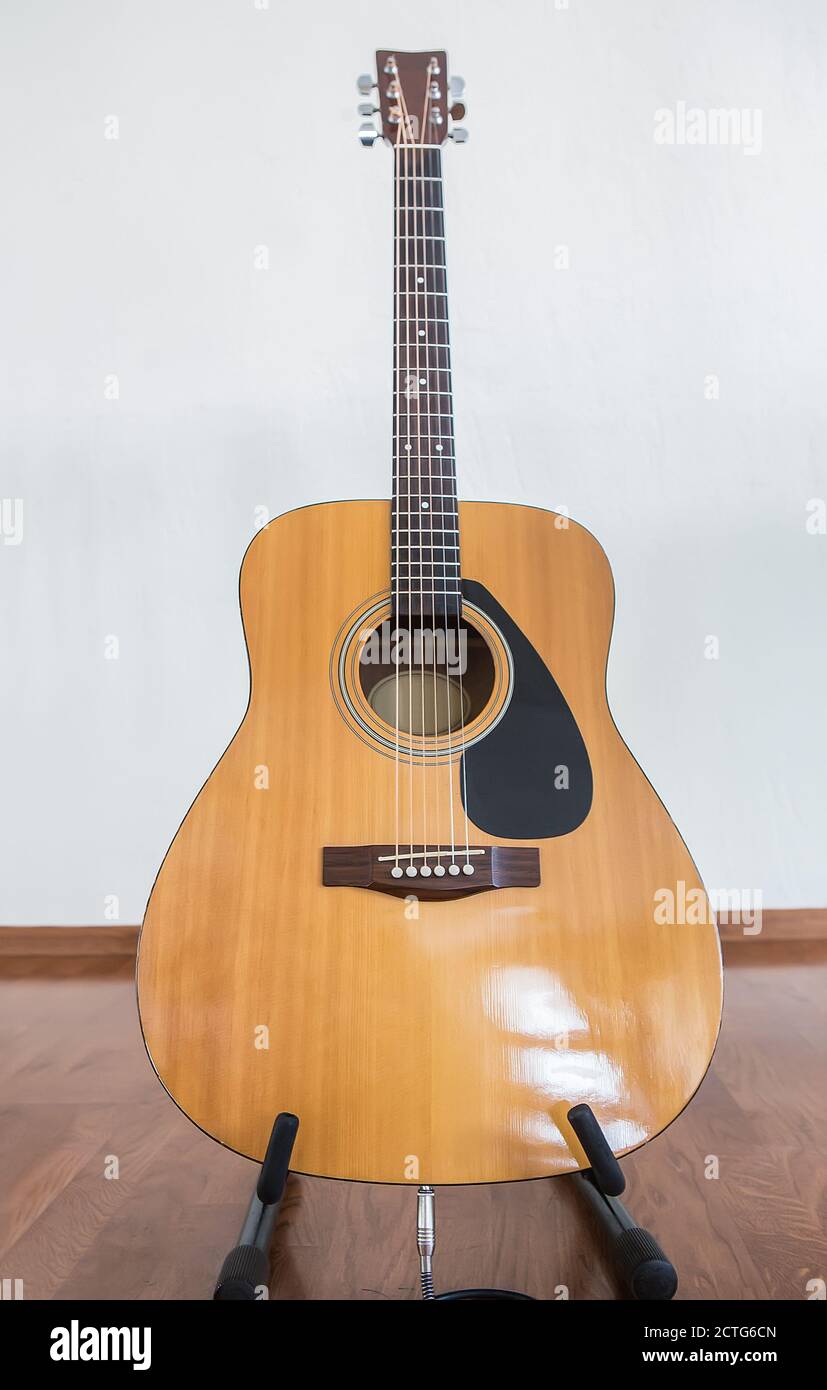 Acoustic guitar indoors near the wall vertically Stock Photo - Alamy