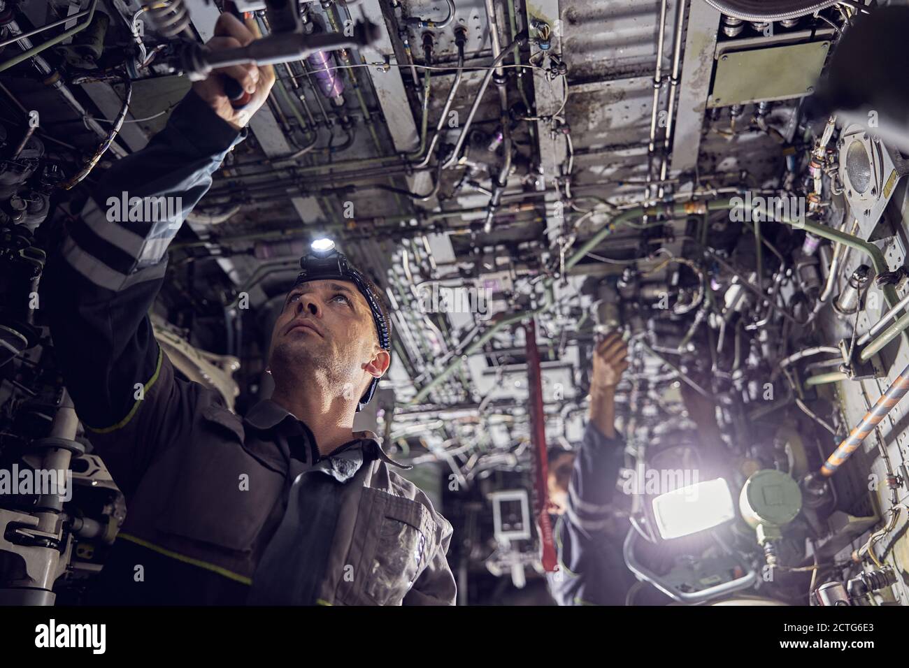 Low angle portrait of aviation mechanic working inside aircraft wearing ...