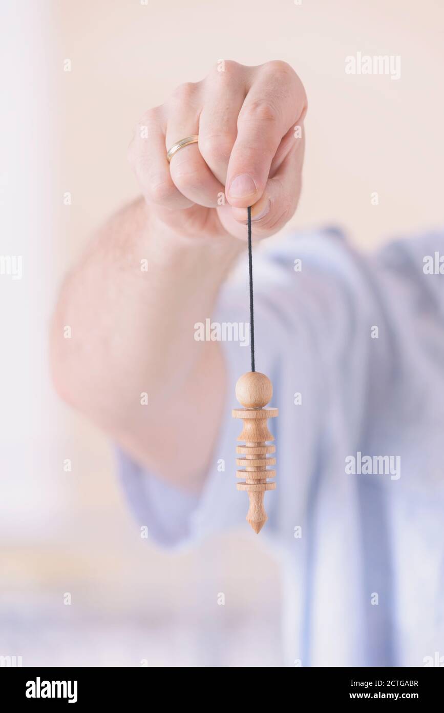 Hand with pendulum, tool for dowsing Stock Photo - Alamy