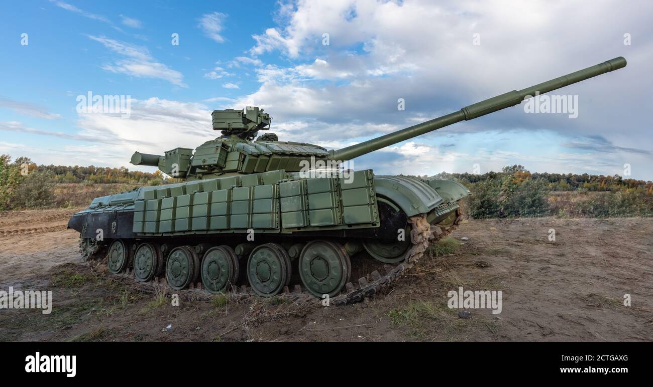 A side shot of russian tank T-64 in the field. Blue cloudy sky as a ...