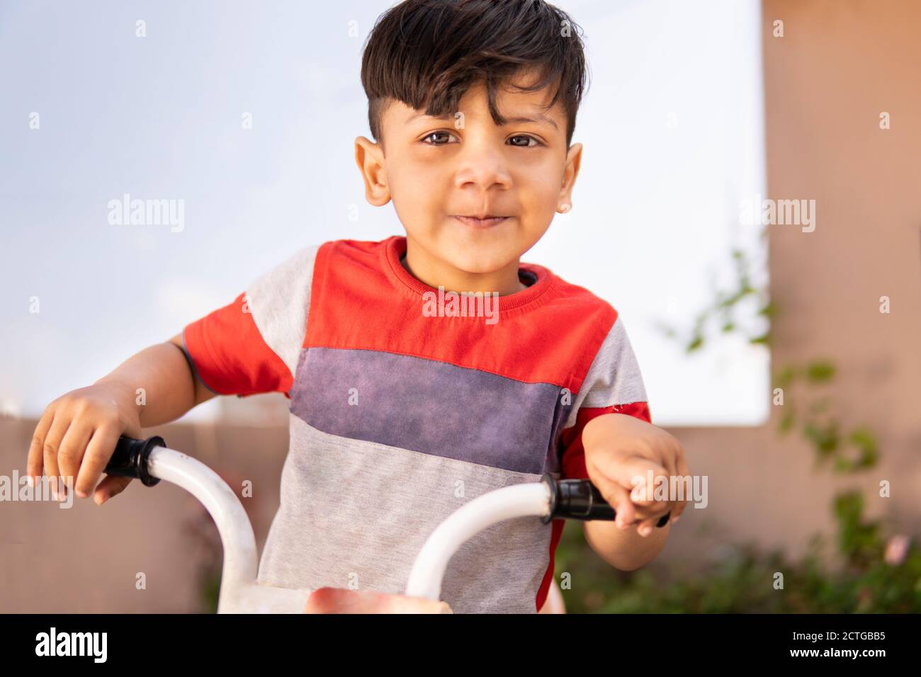 Cute little boy riding a kid tricycle (run bike) on his house rooftop ...