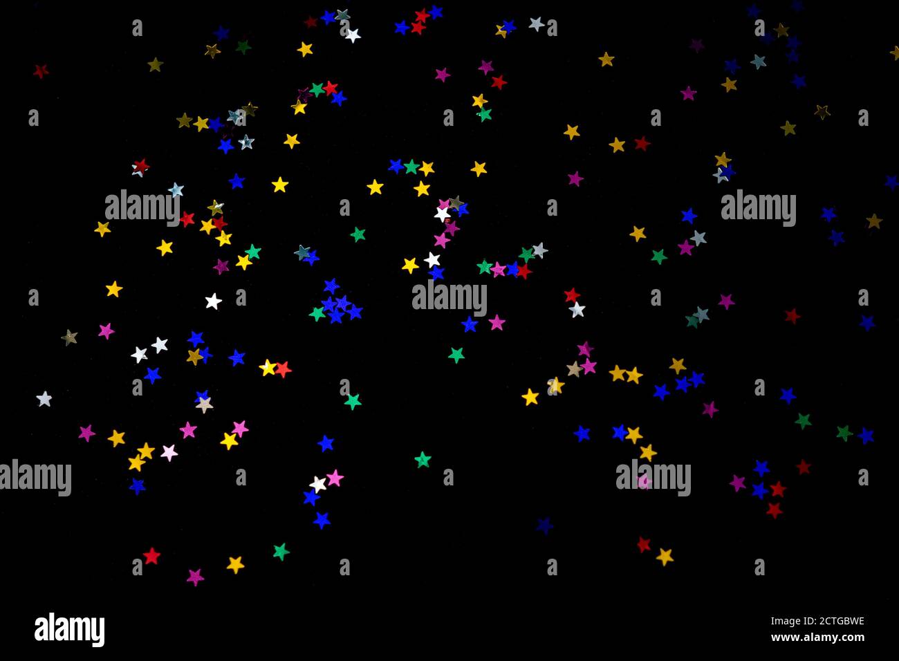 Multi-colored stars on a black background. Festive background of ...