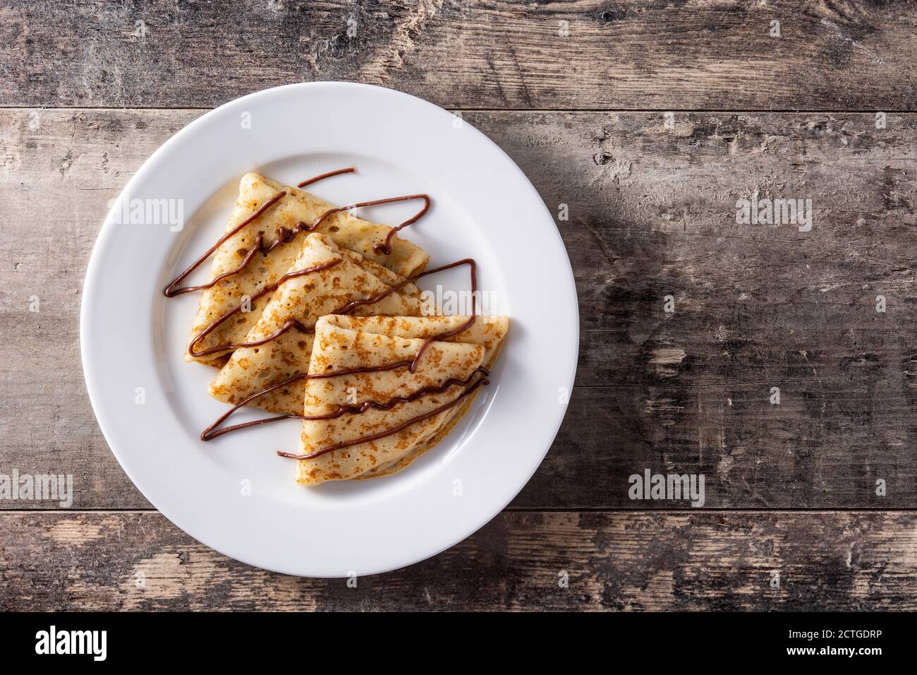 Sweet crepes with chocolate on wooden table Stock Photo - Alamy