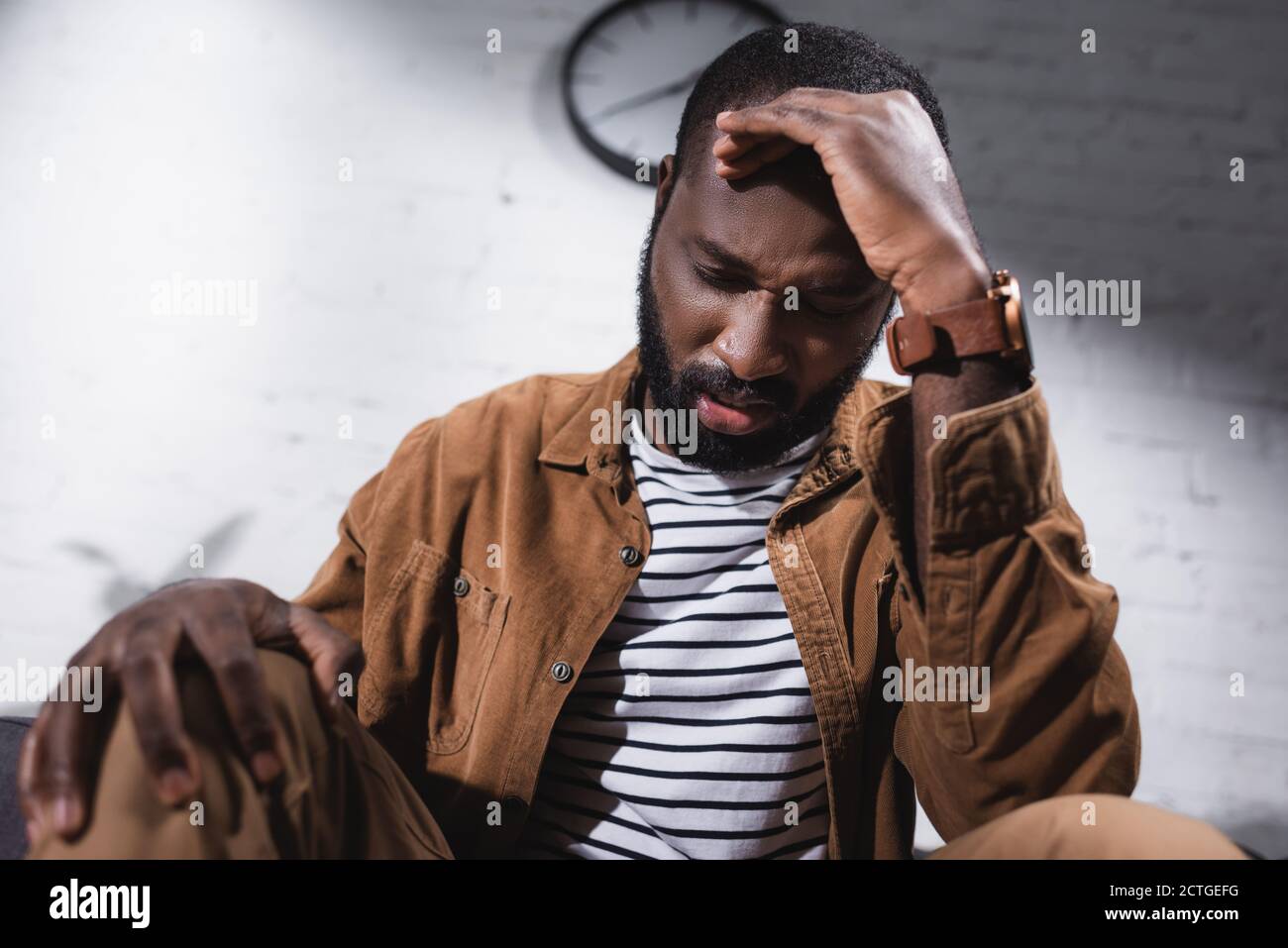 Selective focus of african american man sitting and touching face Stock ...