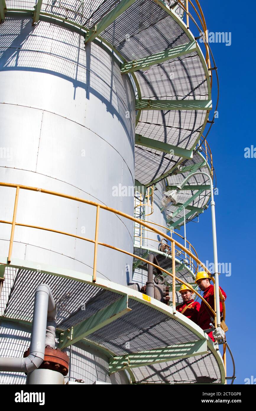 Grey distillation column of oil refinery plant on blue sky background ...