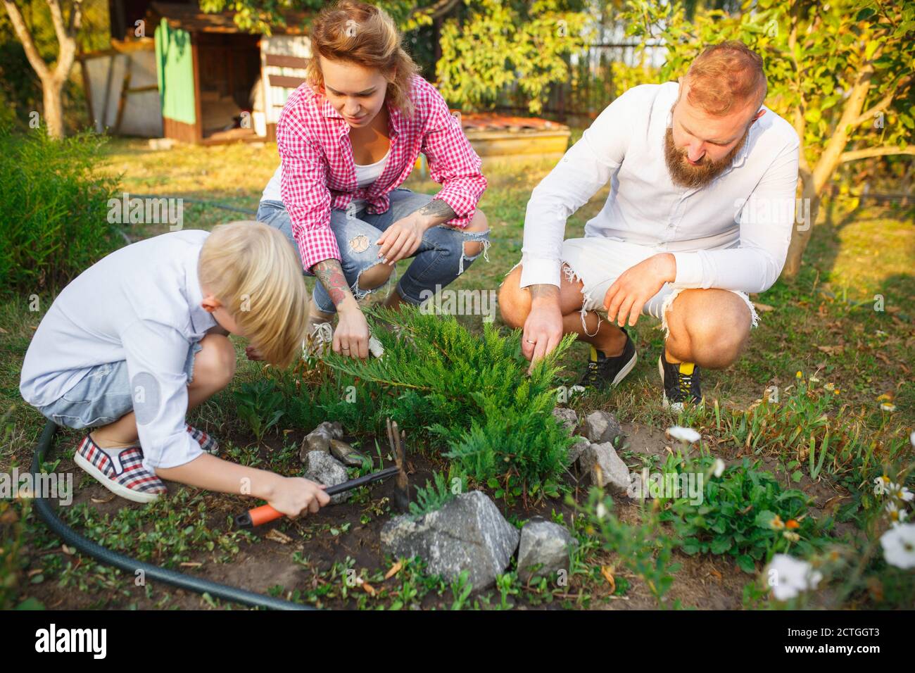 Togetherness and happiness. Happy family during plant care in a garden ...