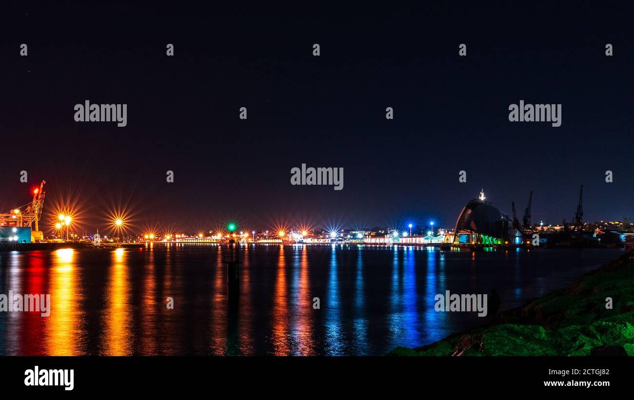 Fremantle harbour at night with a man fishing off the groin in the ...