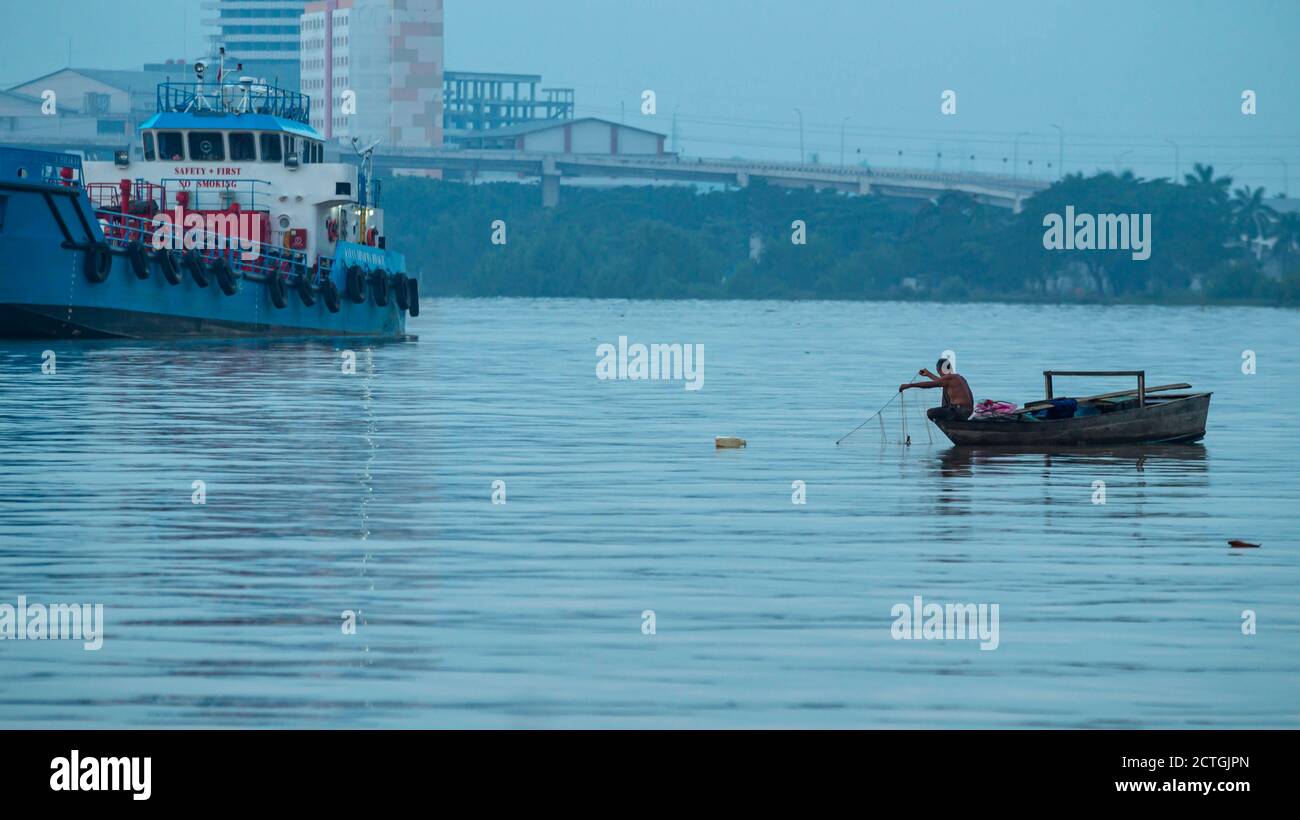 Traditional fisherman checking his fishing net on Mahakam River in the ...