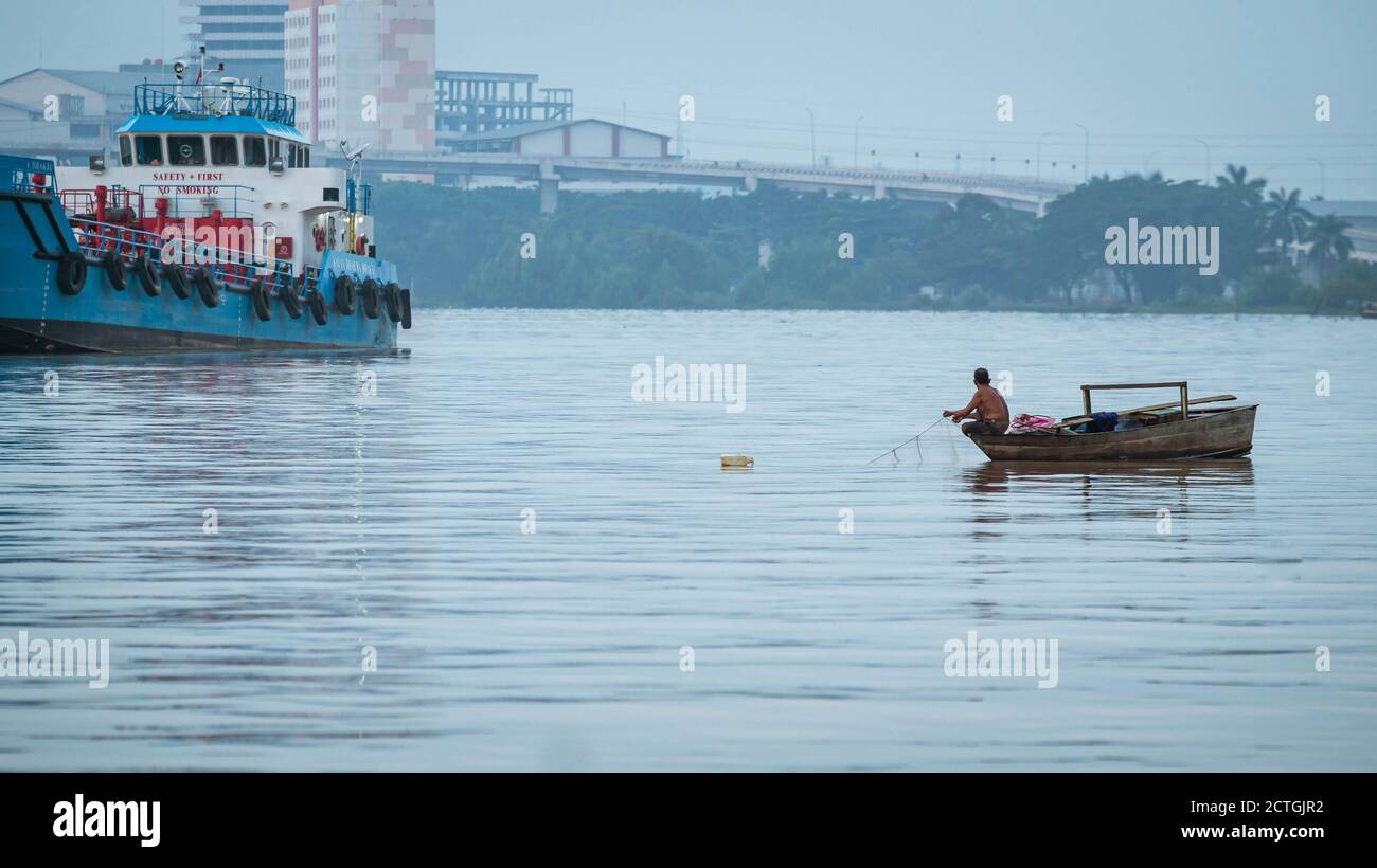Traditional fisherman checking his fishing net on Mahakam River in the ...