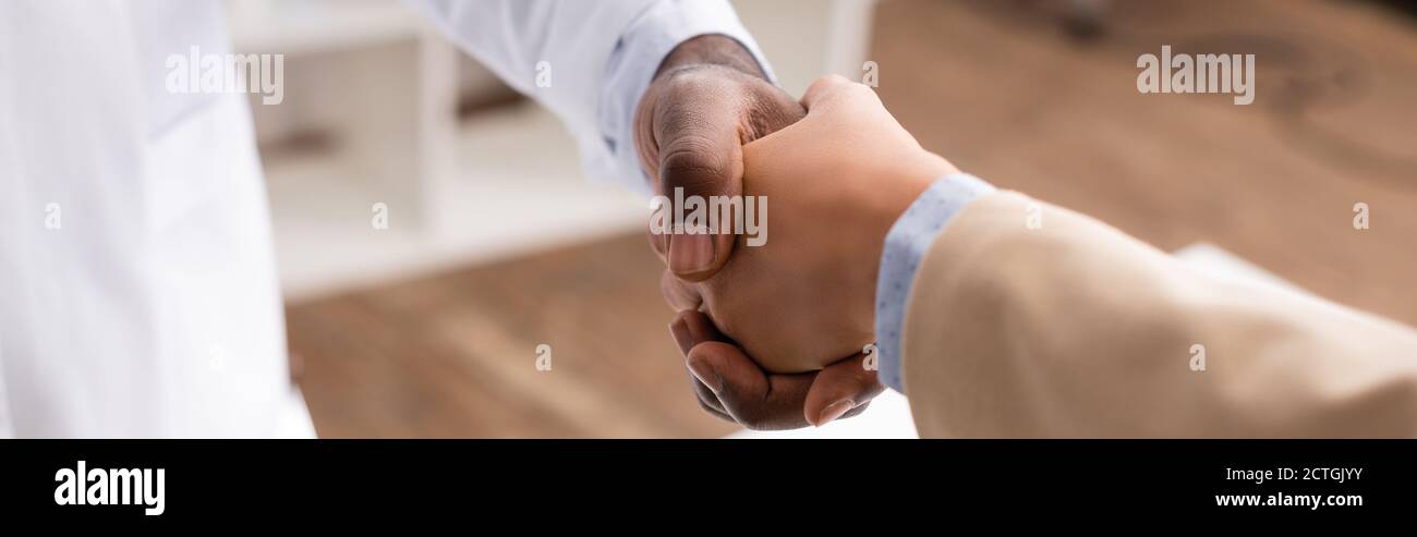 Panoramic crop of african american doctor shaking hands with patient ...