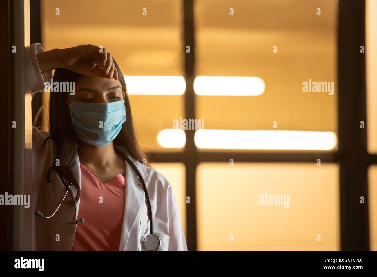Doctor leaning on the door and taking a break after a hectic day at ...