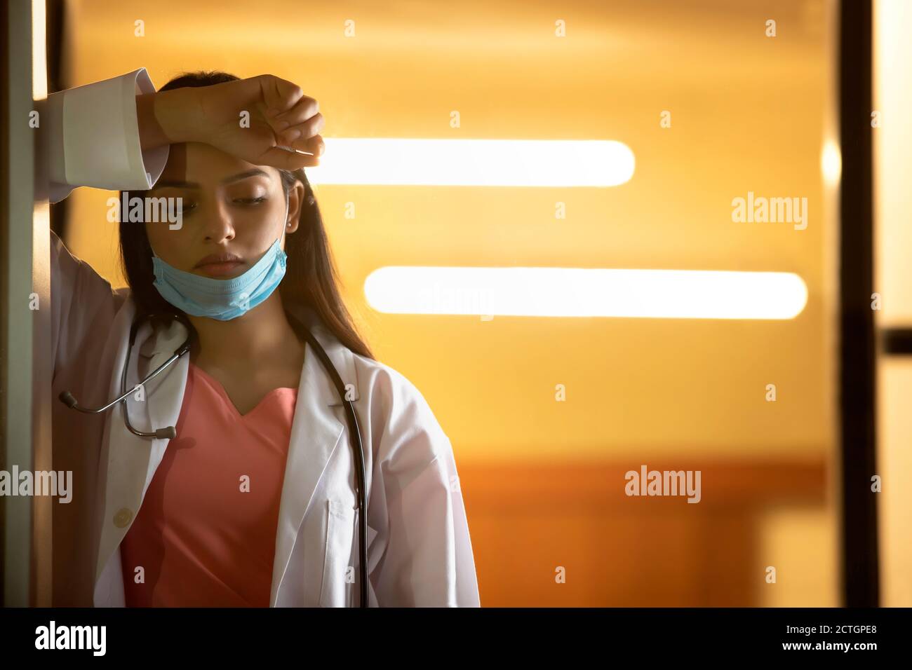 Doctor leaning on the door and taking a break after a hectic day at ...