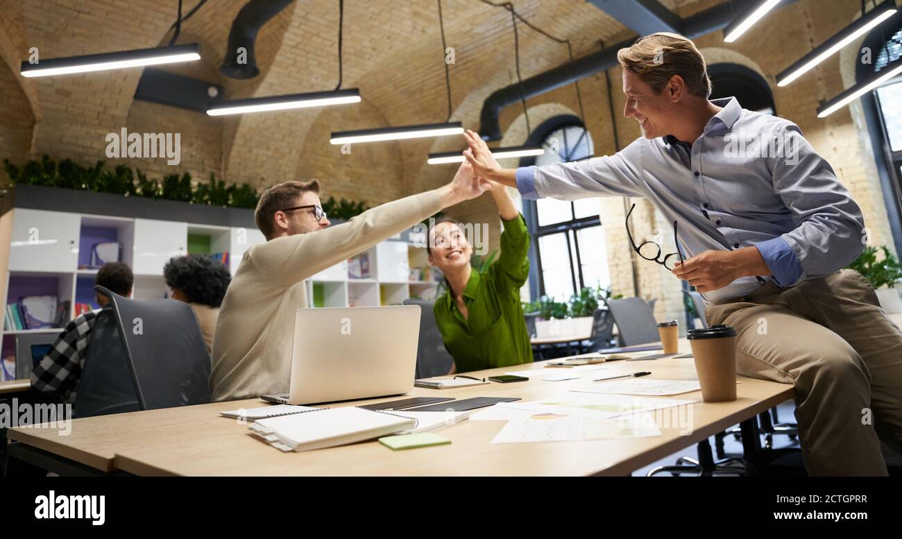 Celebrating success. Happy multiracial business people giving high five ...