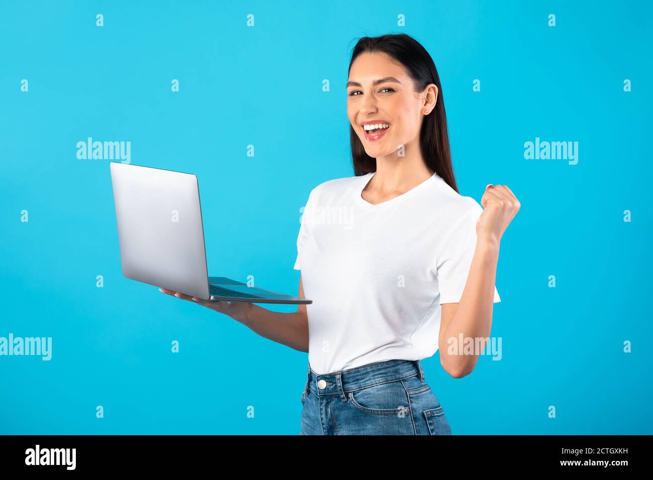 Happy female model celebrating win holding laptop Stock Photo - Alamy