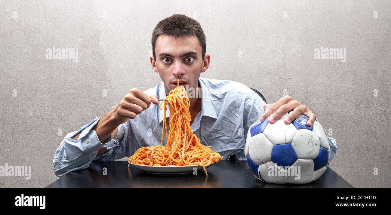 an young man eating spaghetti caught in football Stock Photo - Alamy